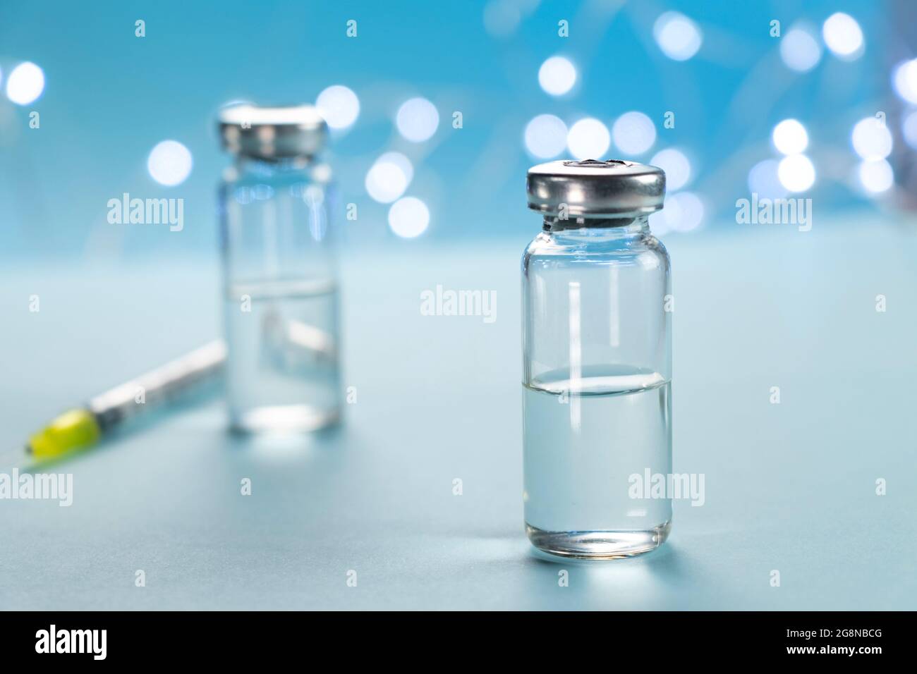 Two bottles of vaccine and syringe injection on blue background ...
