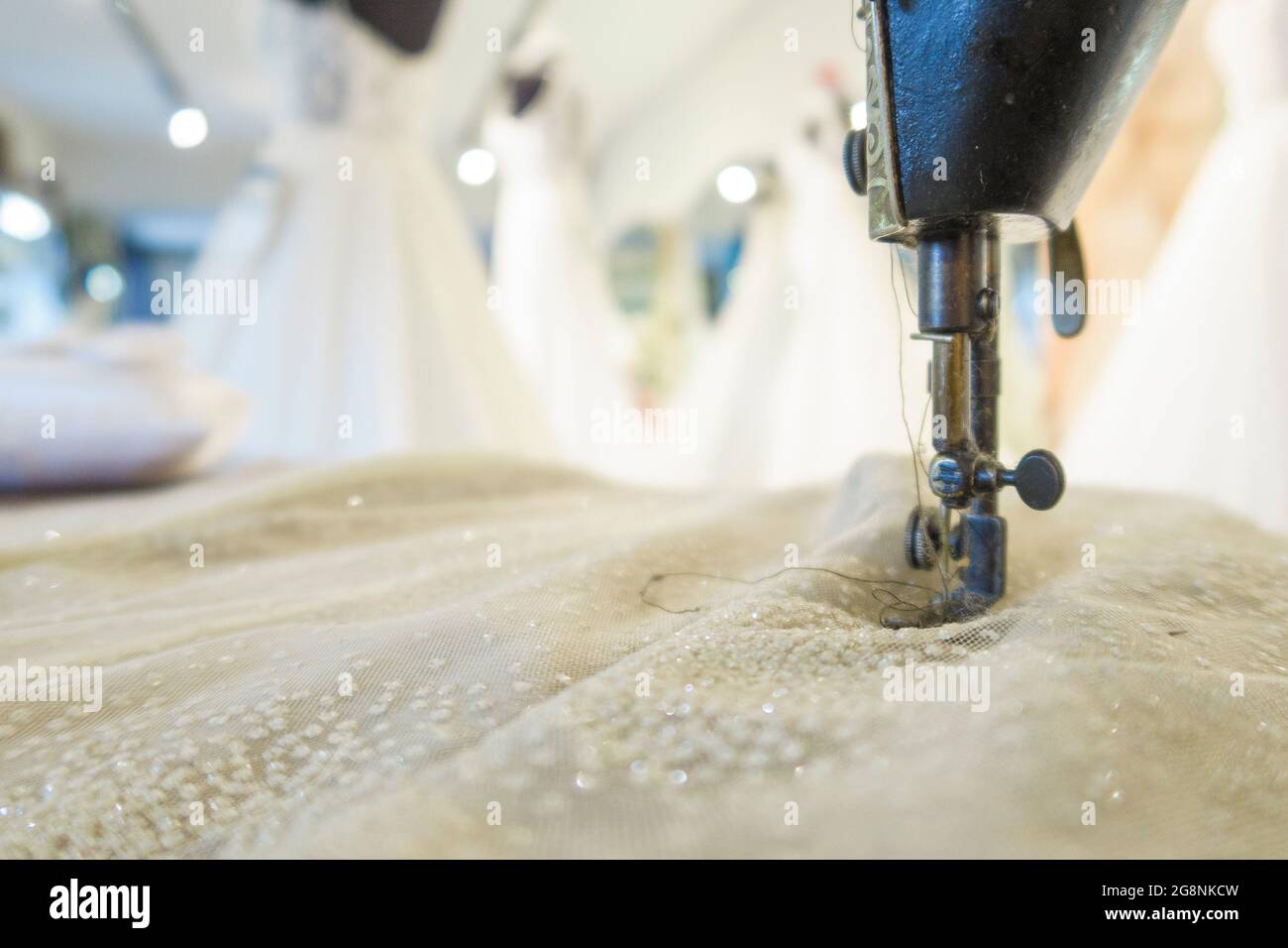 Tailoring detail for bridal dresses with a sewing machine and white ...