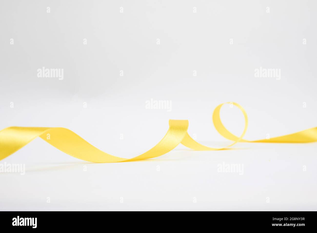 long yellow ribbon, white background Stock Photo - Alamy