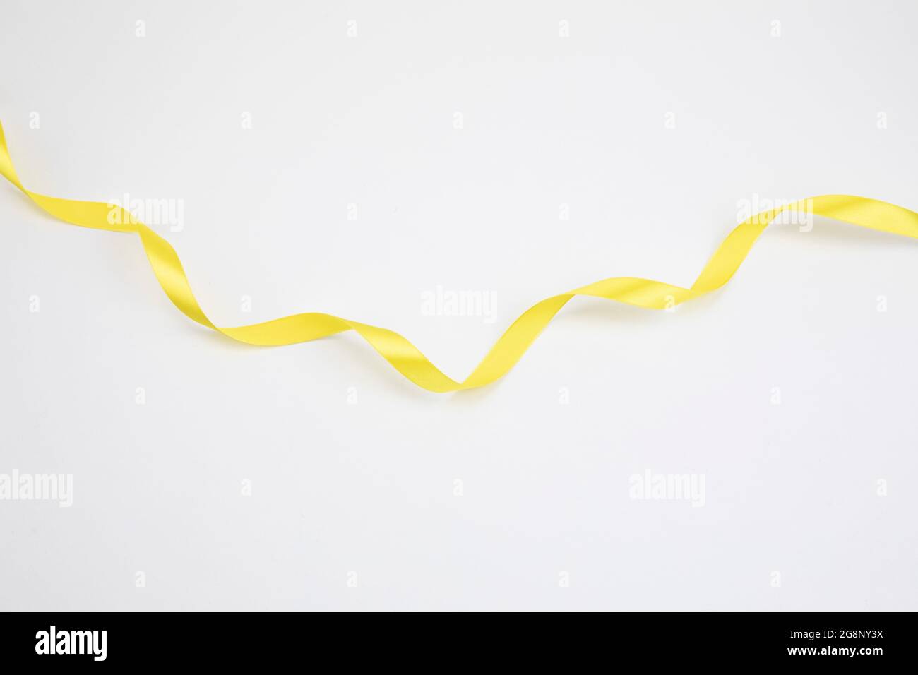 long yellow ribbon, white background Stock Photo - Alamy
