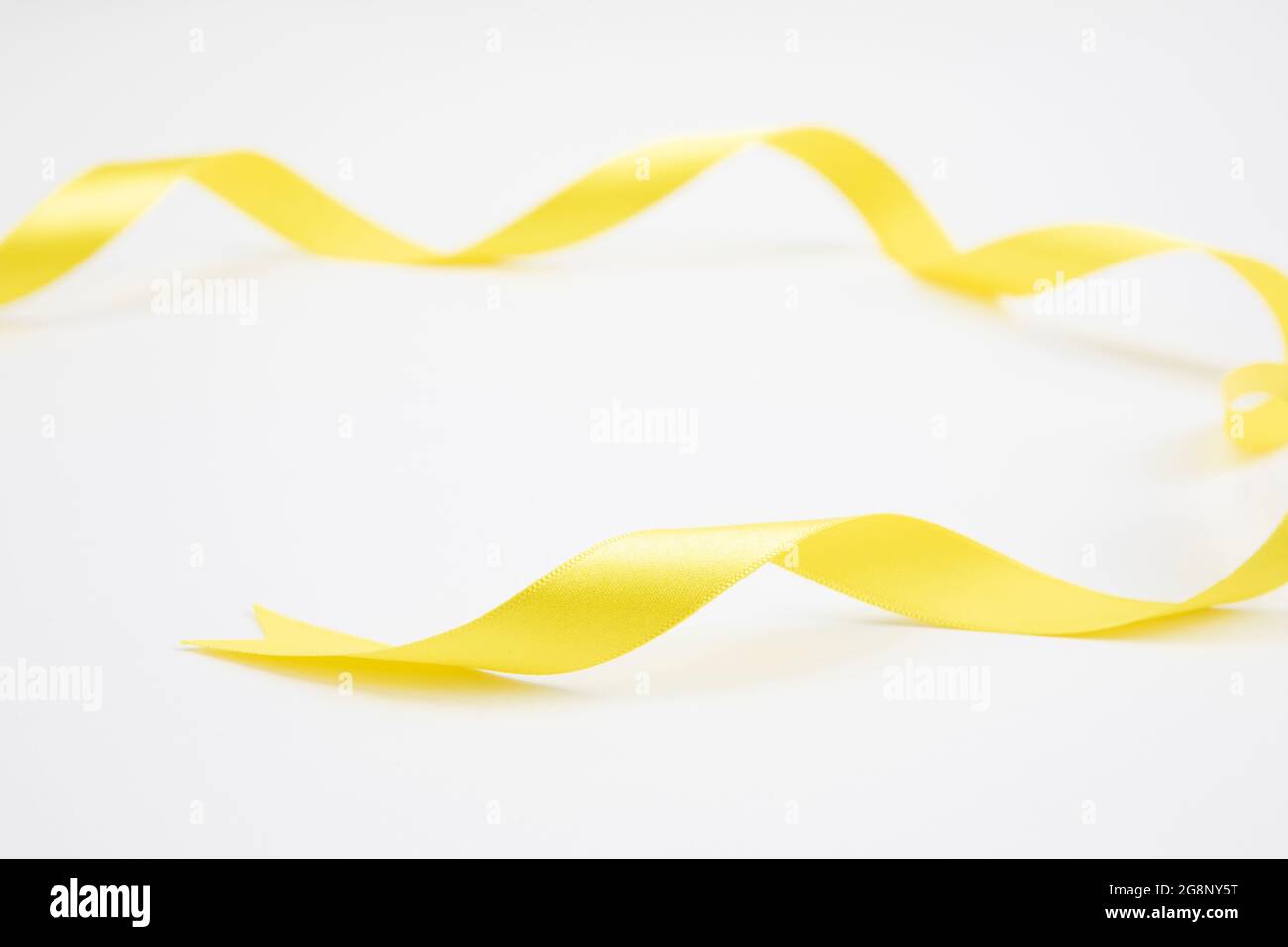 long yellow ribbon, white background Stock Photo - Alamy