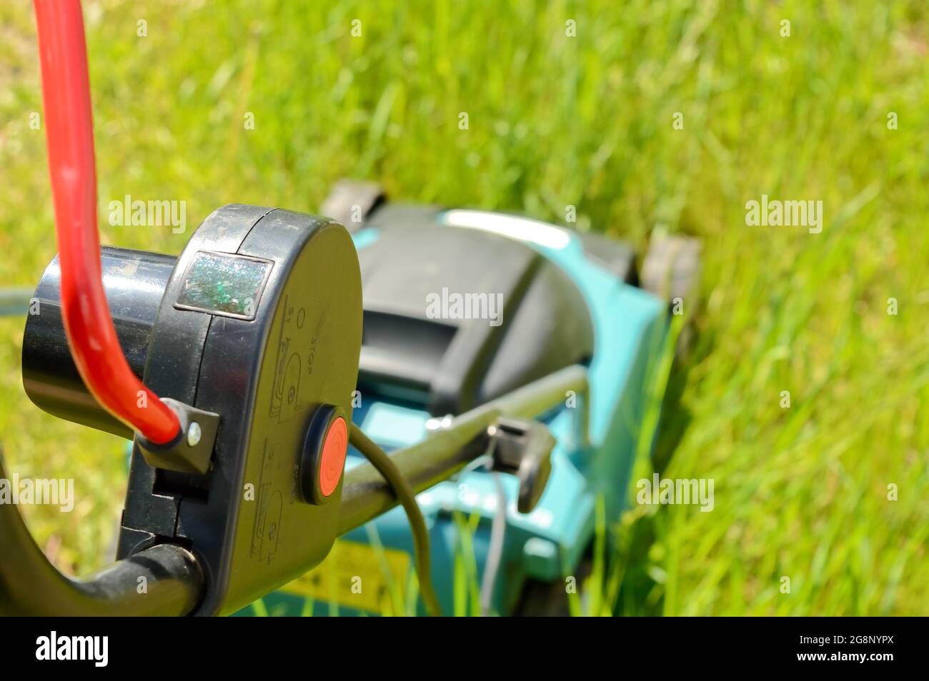 electric lawn mower handle with red power button Stock Photo - Alamy