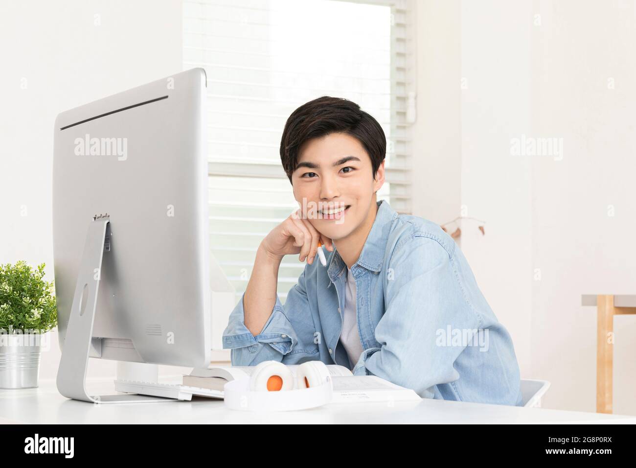 young Asian man smiling at computer monitor Stock Photo - Alamy