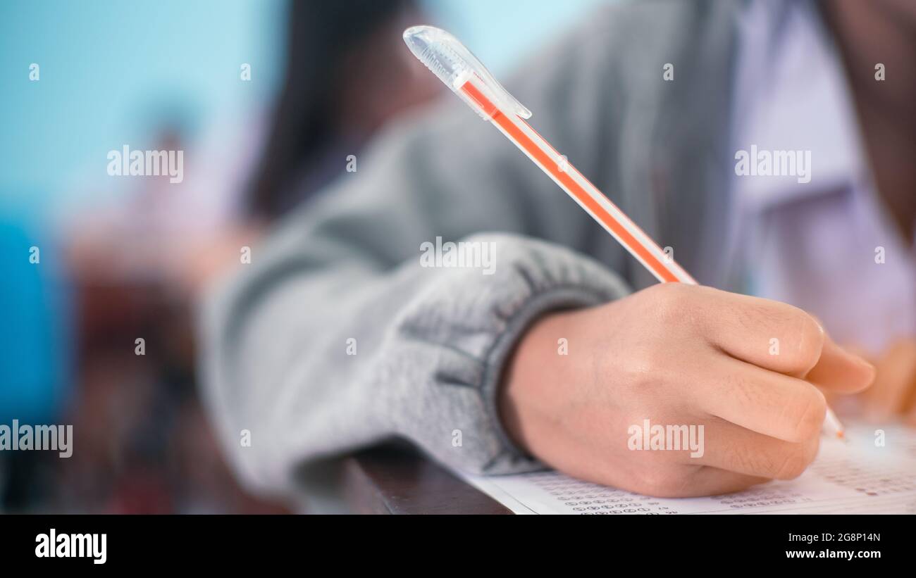 Students writing and reading exam answer sheets exercises in classroom ...