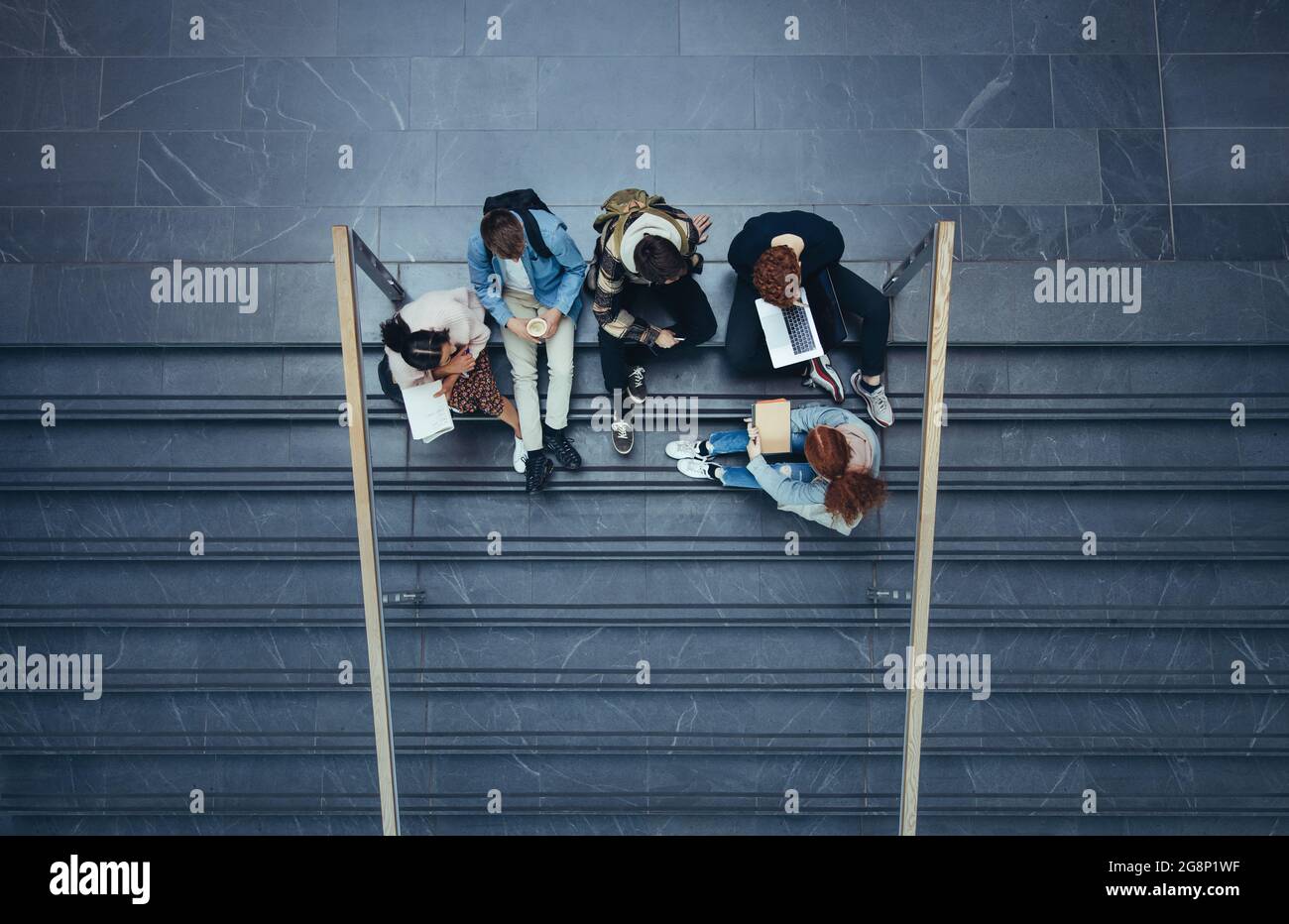 Youngsters in university sitting on steps studying. Students sitting in ...