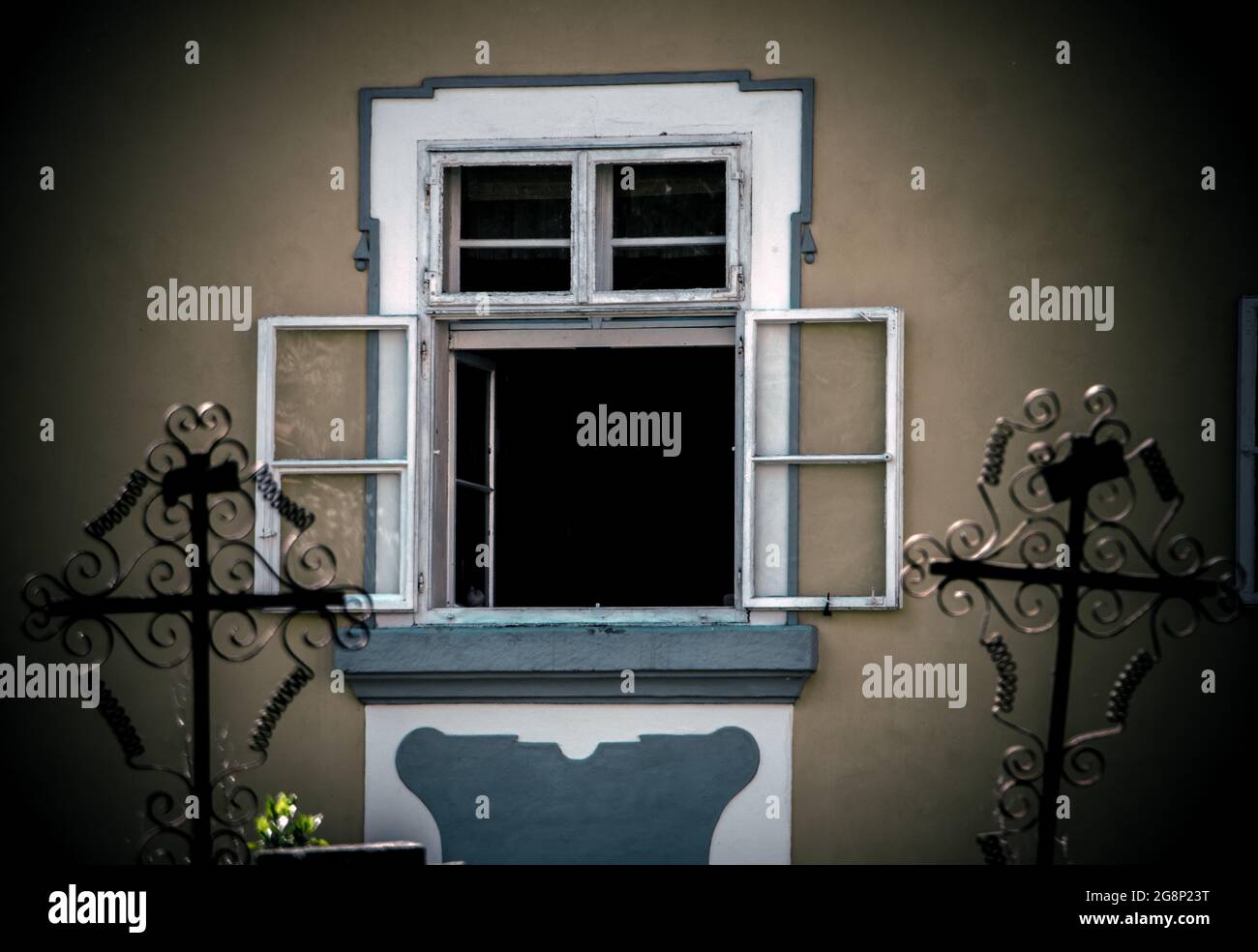 Old crosses on graves under the open window of a building with a ...
