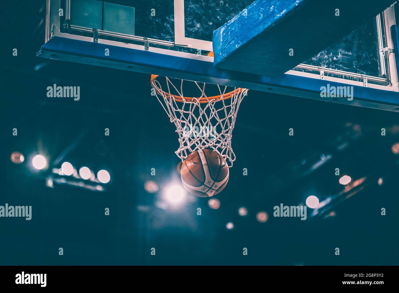 Ball in hoop at basketball game Stock Photo - Alamy