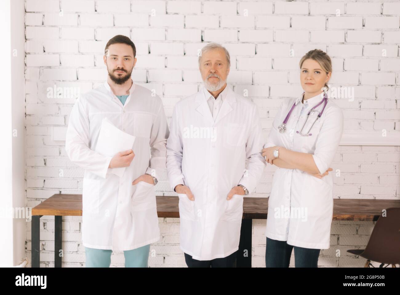 Portrait of three doctors wearing hospital uniform posing standing on ...