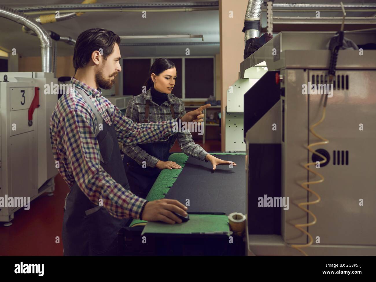 Two employees of a shoe factory work together with a machine for ...