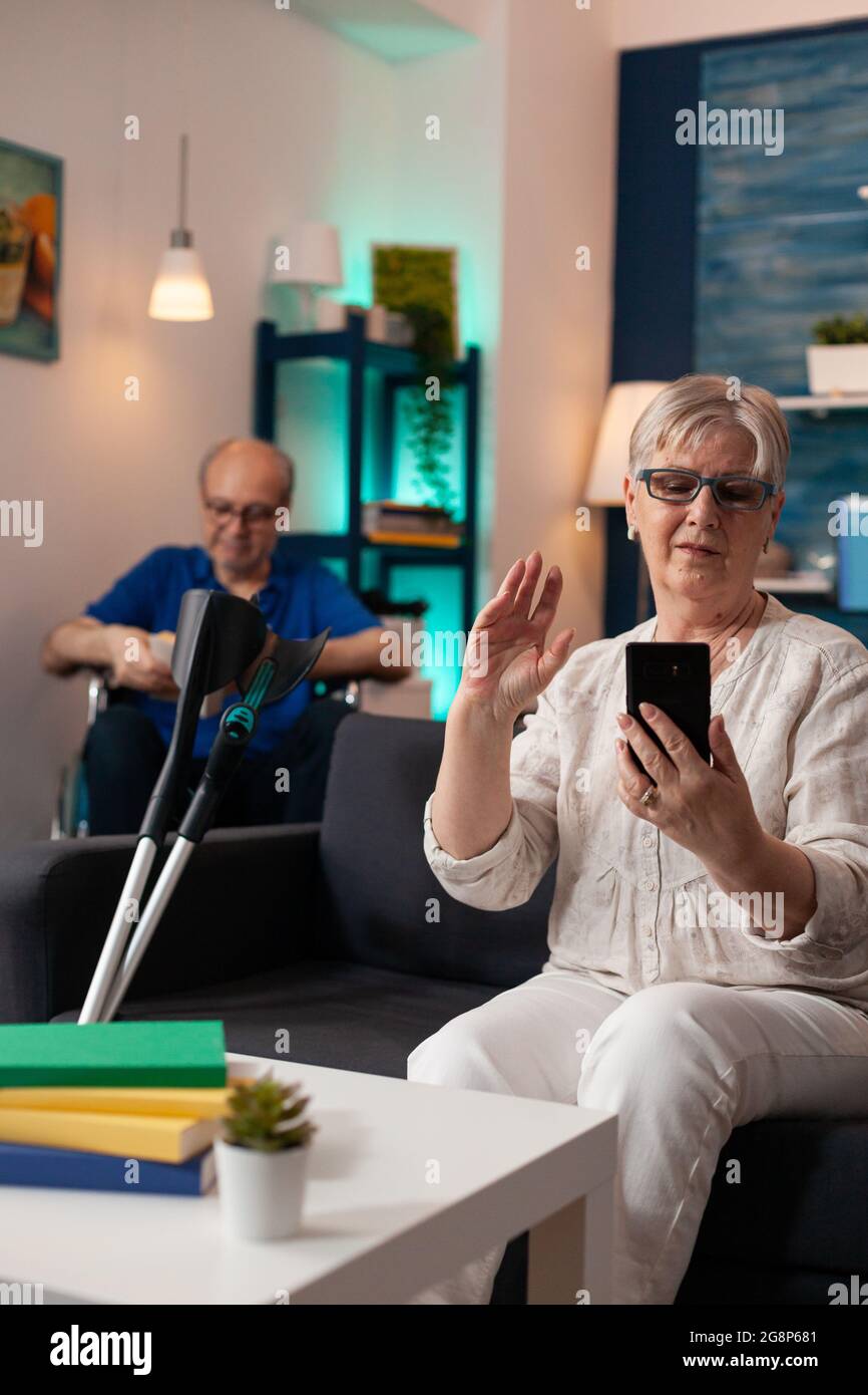 Mature retired couple on modern video call at home using smartphone ...