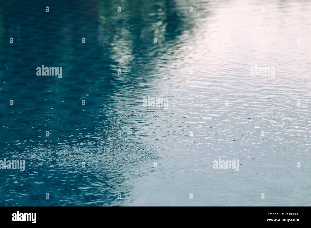 rain drops on the surface of water in a puddle with graduated shade of ...