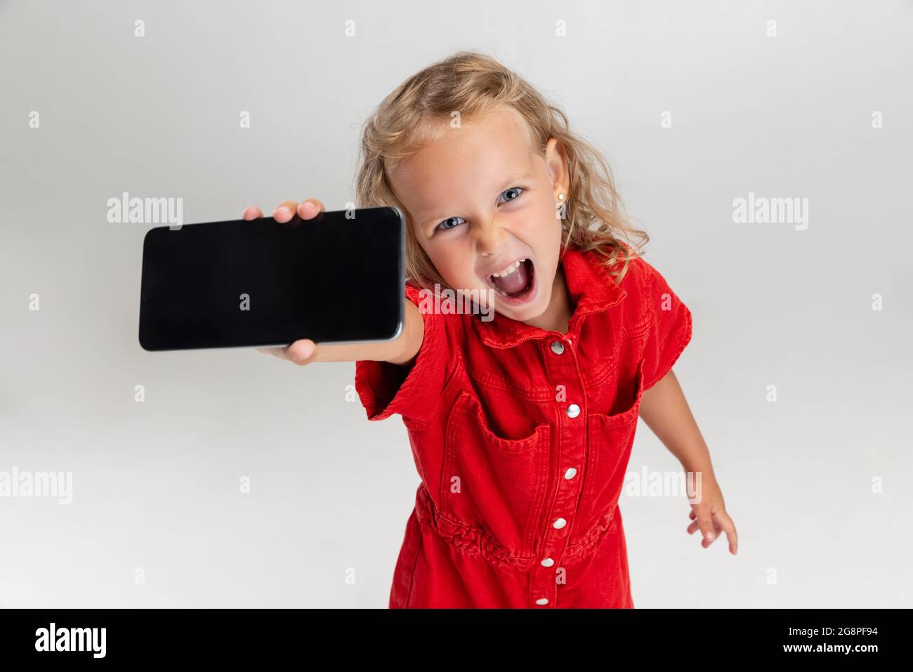 Showing device screen. One little screaming preschool girl holding ...