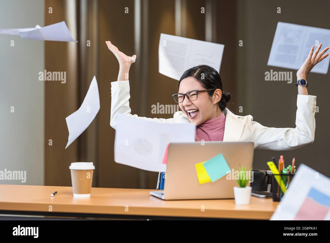 Asian businesswoman angry throwing papers over the herself in office ...