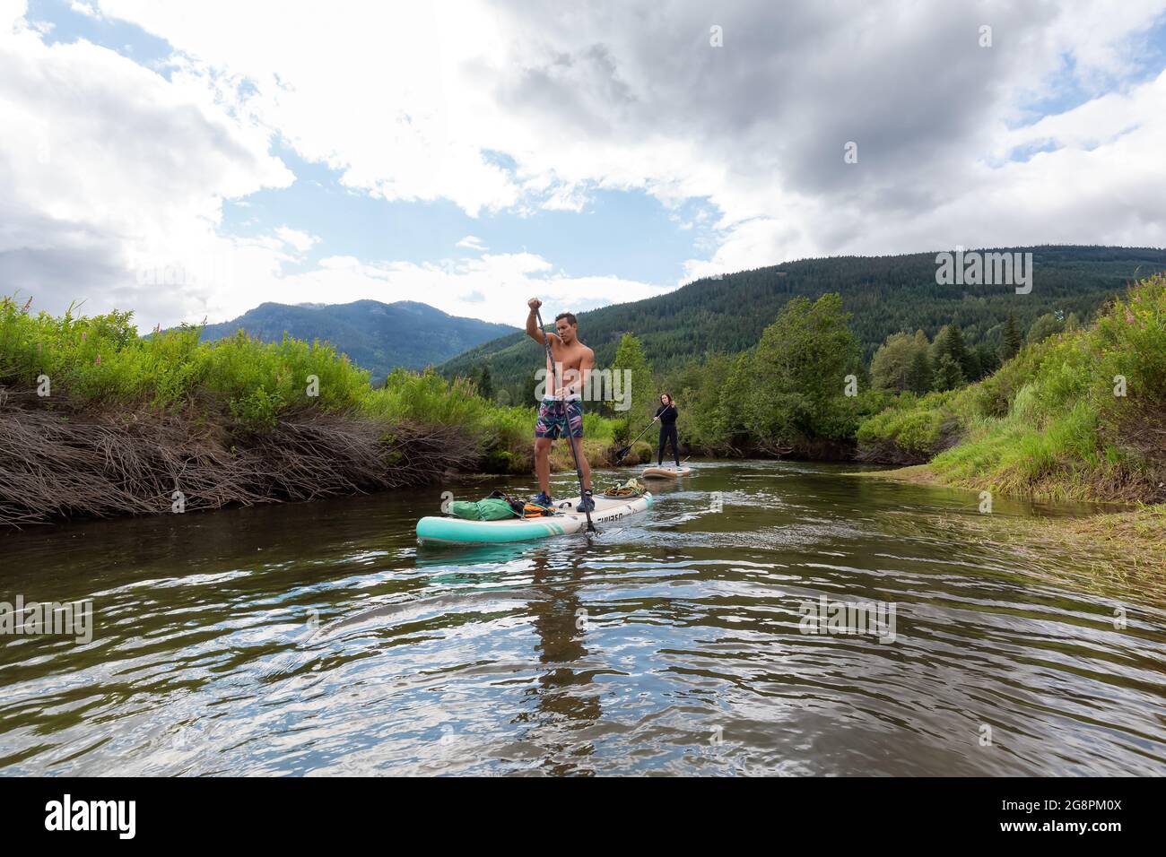 Adventurous people paddle boarding in a river Stock Photo - Alamy