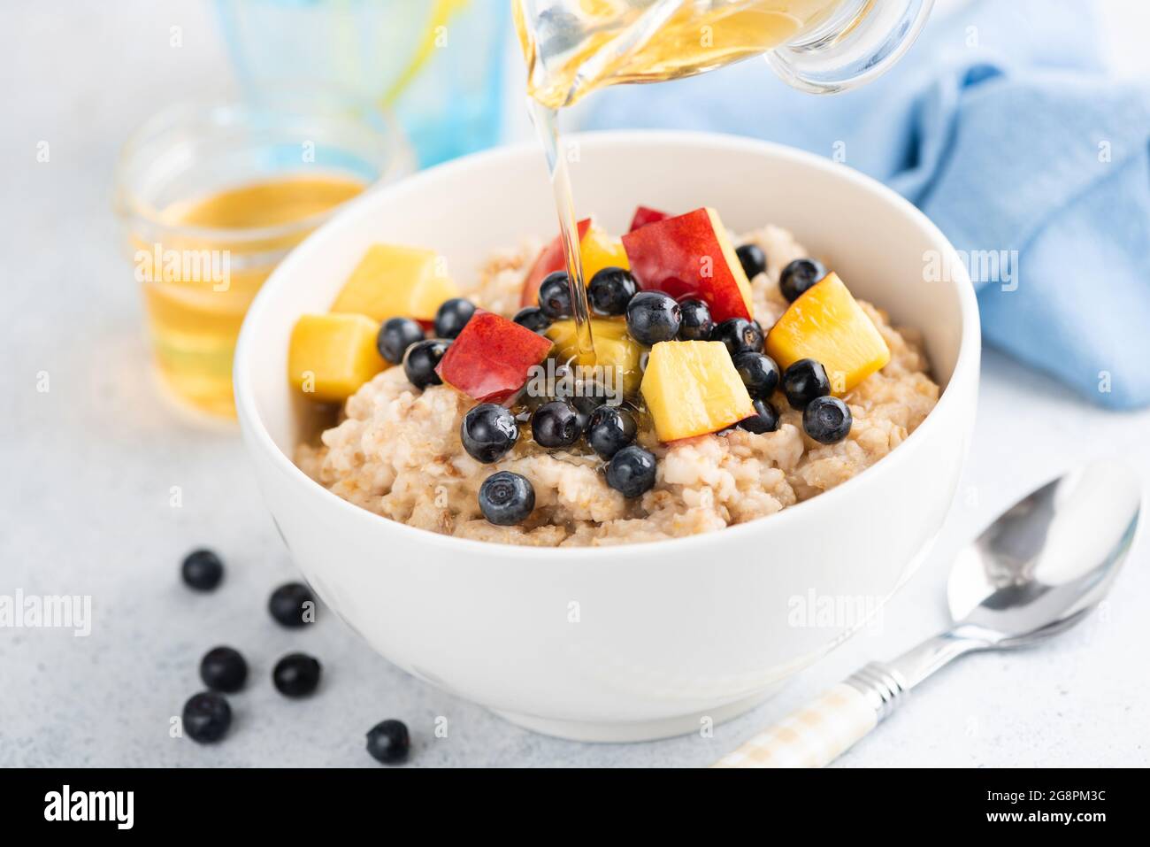 Cooked oatmeal with peach and blueberries in a bowl, closeup view Stock ...