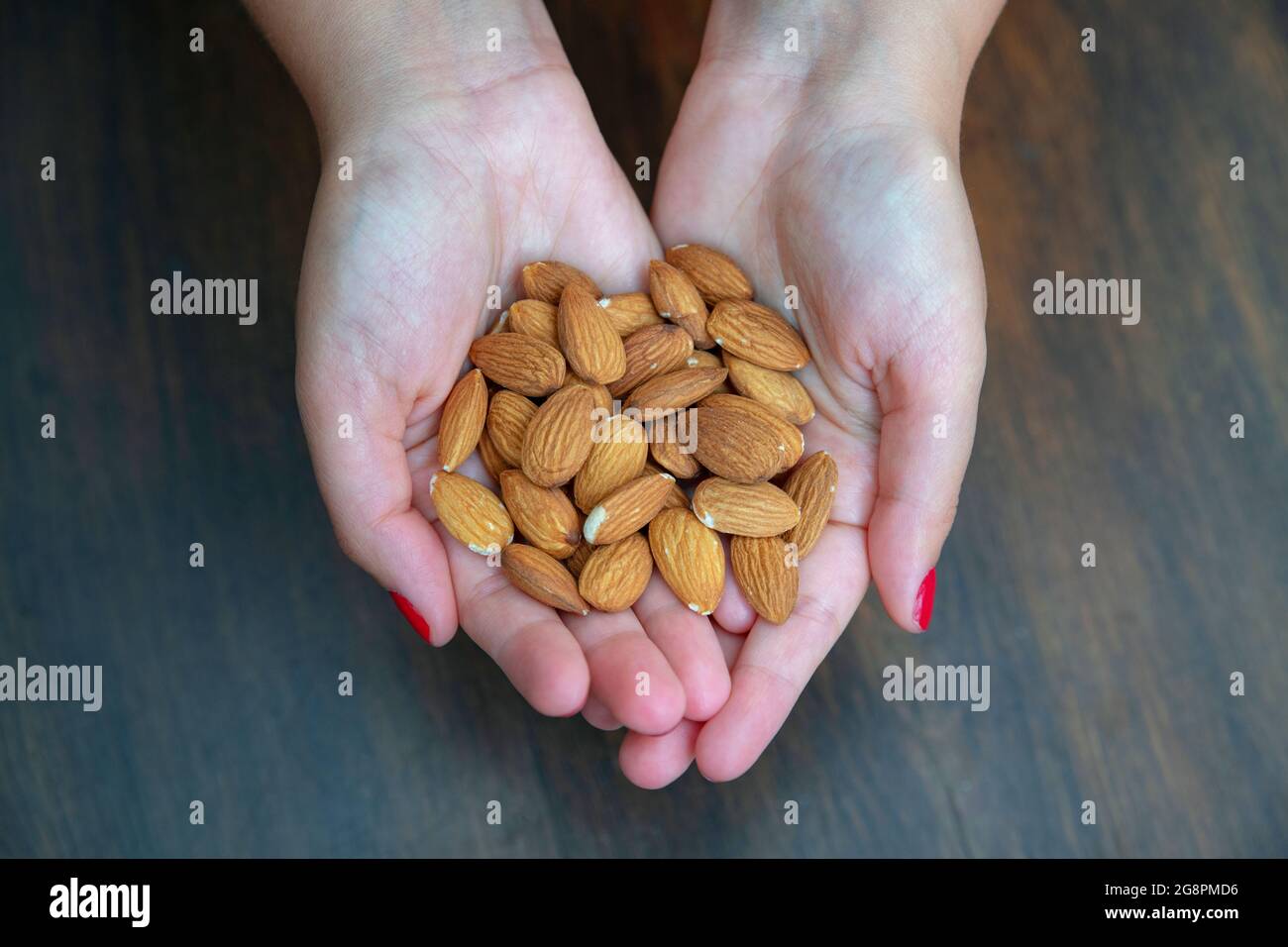 Woman holding a handful of almonds, the edible seeds of Prunus dulcis ...