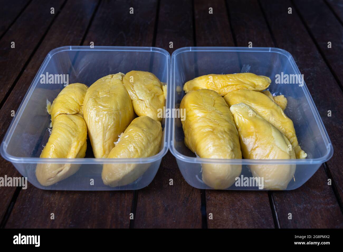 Golden yellow musang king durian pulp flesh in two containers on wooden ...