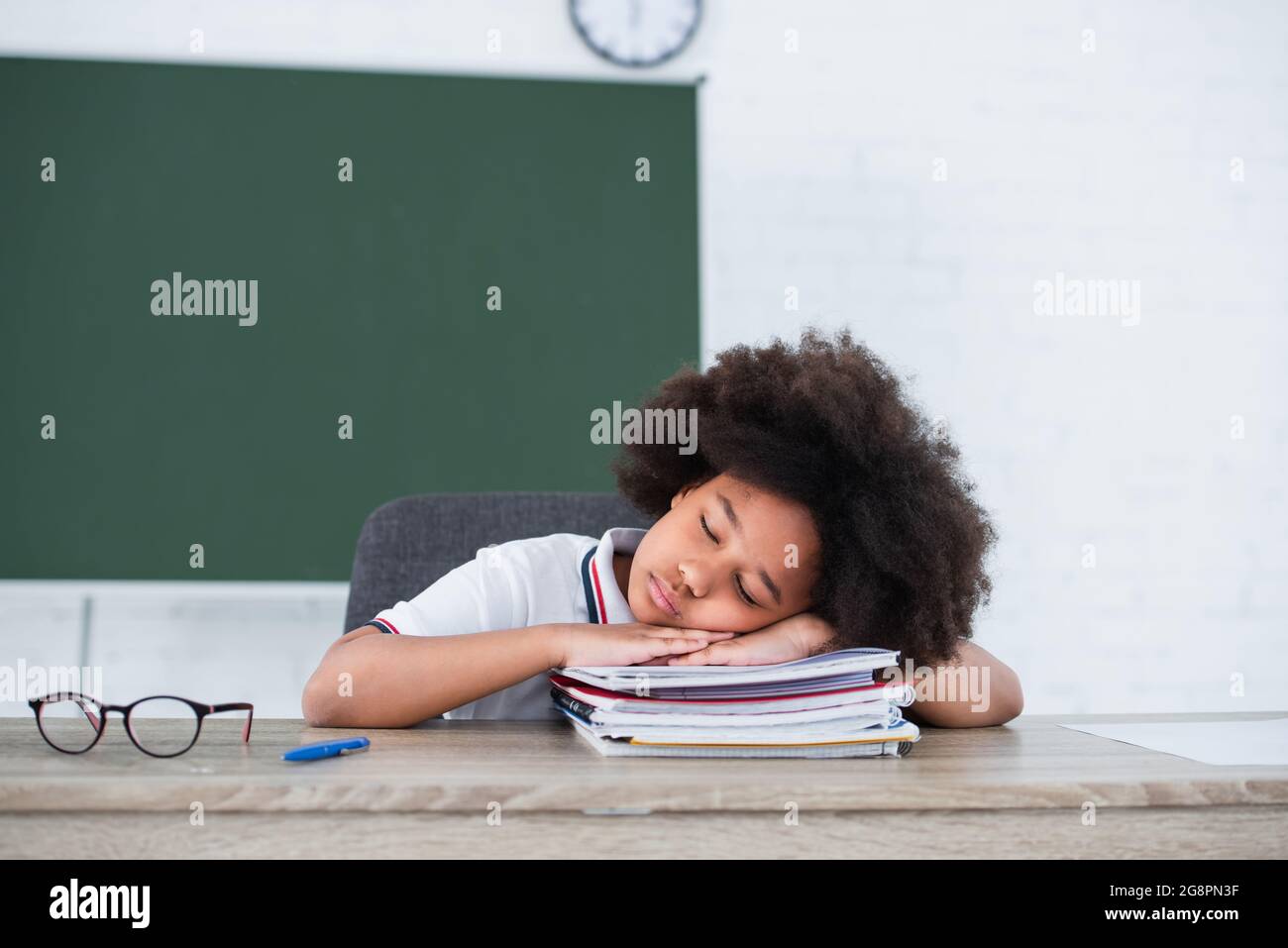 African american schoolchild sleeping on notebooks near eyeglasses in ...