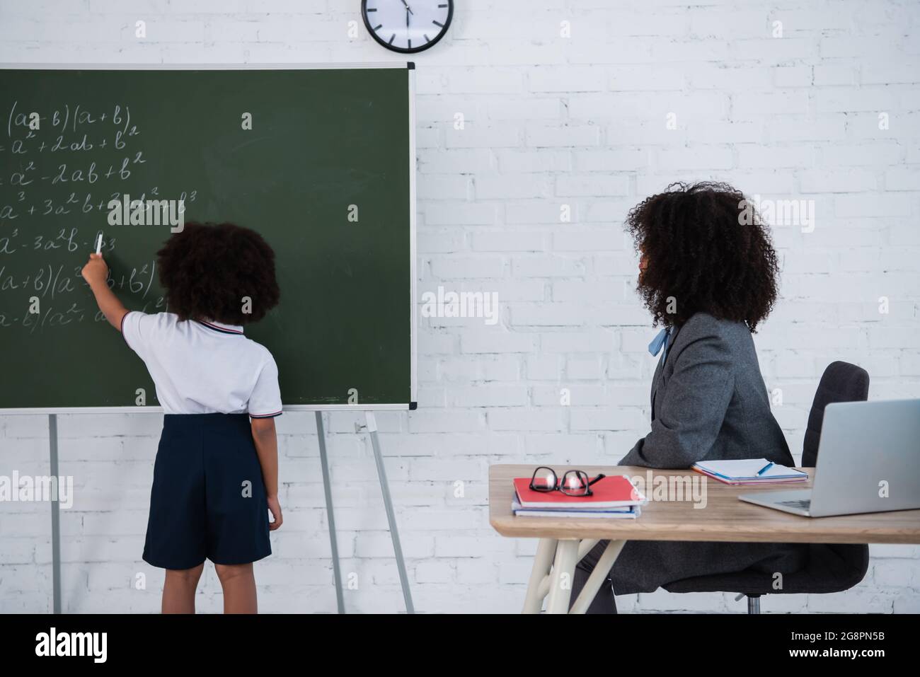 African american kid writing mathematics formula on chalkboard near ...