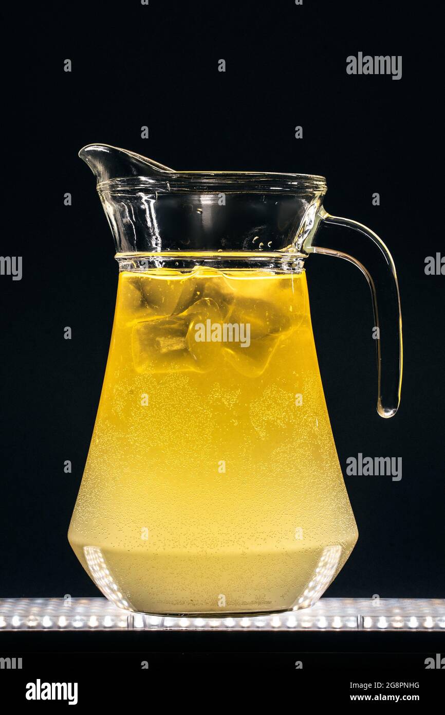 glass jug with refreshing lemonade fizzy yellow drink or ice on black ...