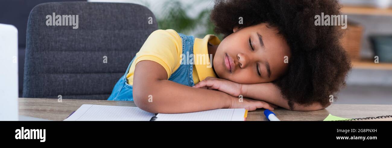 African american kid sleeping near notebook at home, banner Stock Photo ...