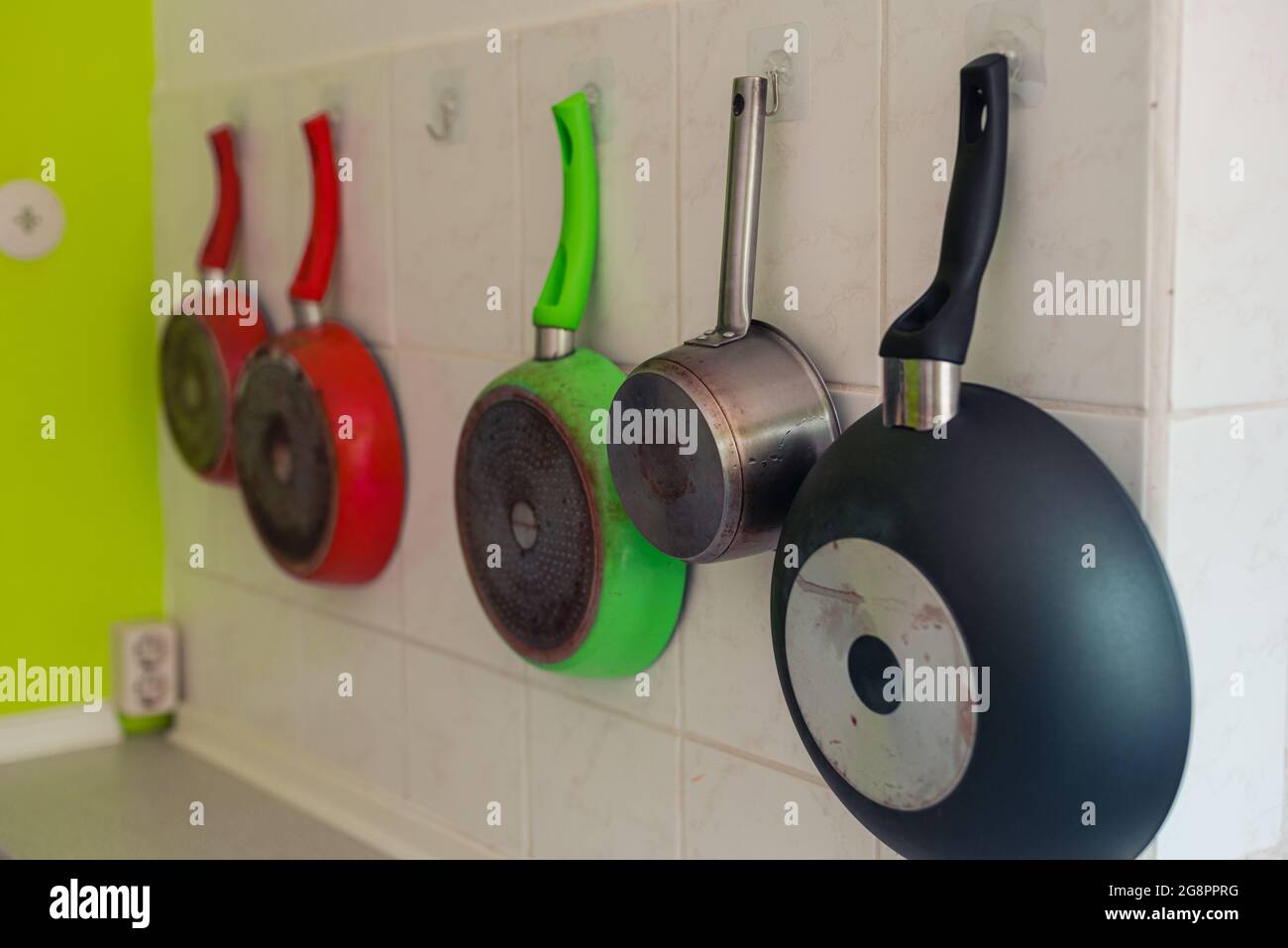 Closeup shot of frying pans of different sizes hung on kitchen wall ...