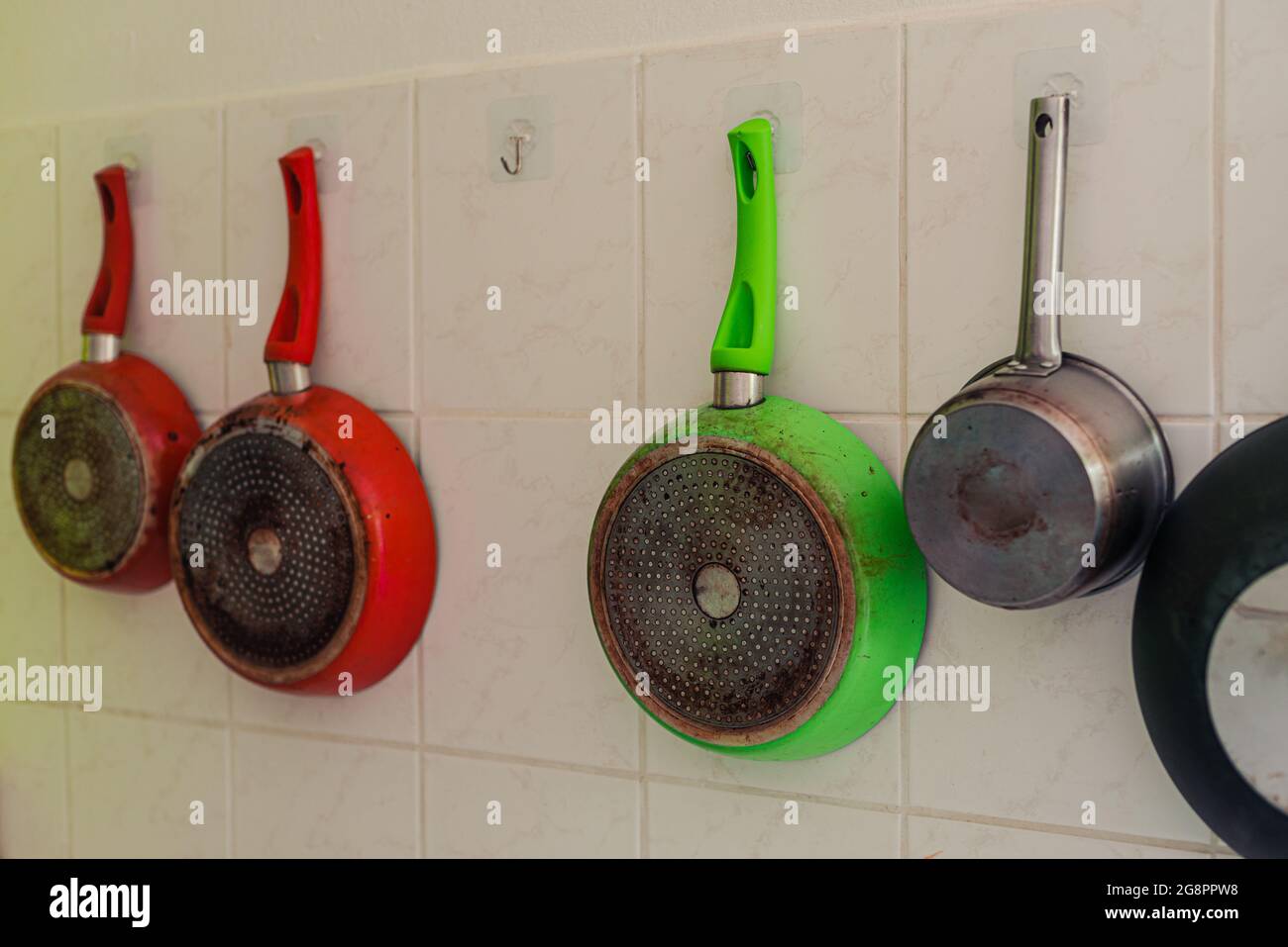 Closeup shot of frying pans of different sizes hung on kitchen wall ...