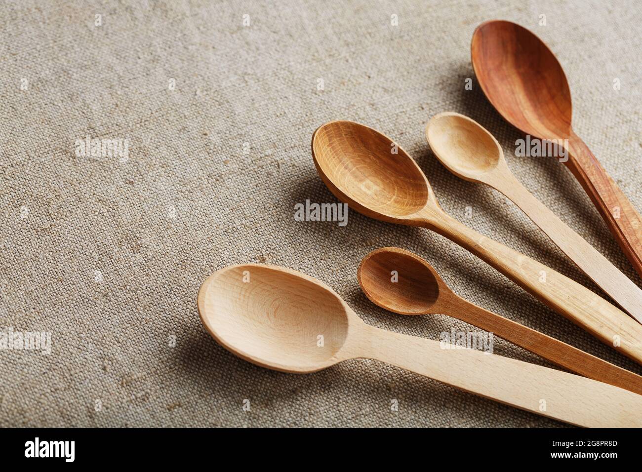 Natural wood spoons in a row on burlap fabric. Natural natural ...