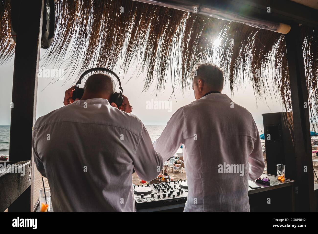 Back view of disc jockeys playing music for tourist people at club ...