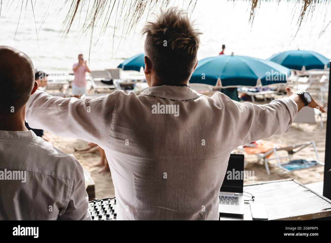 Back view of disc jockeys playing music for tourist people at club ...
