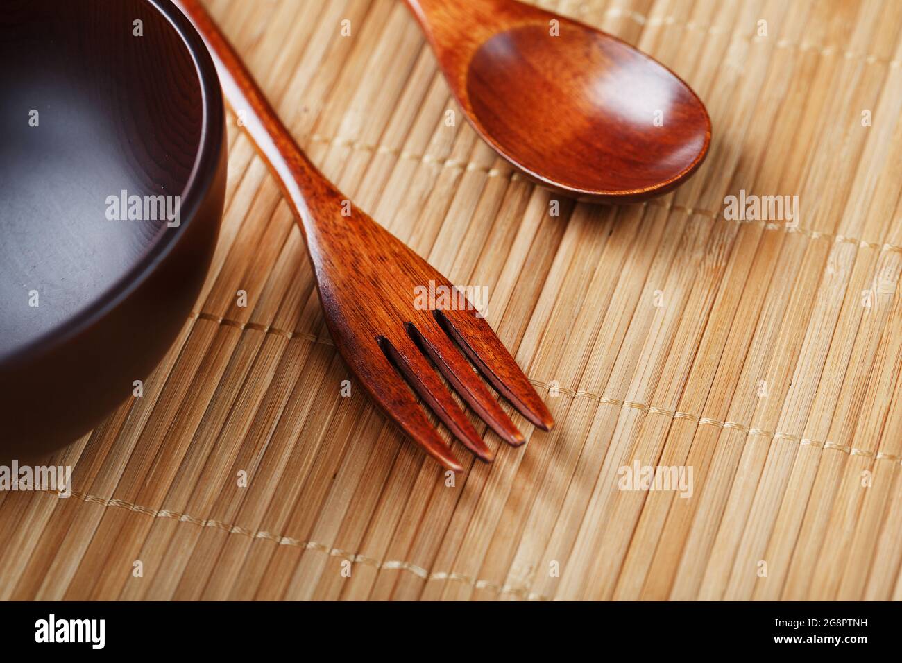 Natural wood plate, spoon and fork on a bamboo backing. Asian food ...