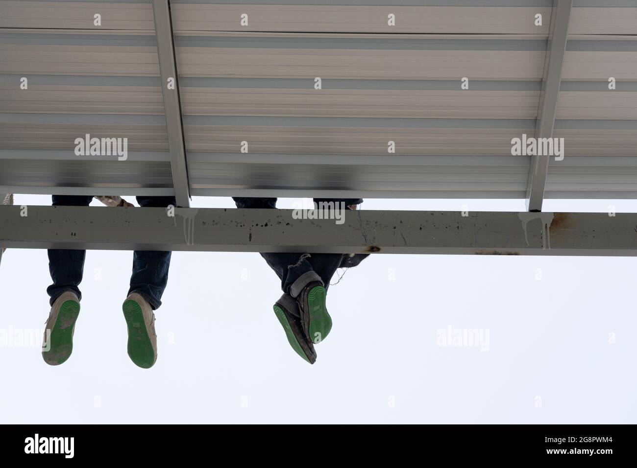 two men sitting, hanging leg with blue jeans on the roof Stock Photo ...