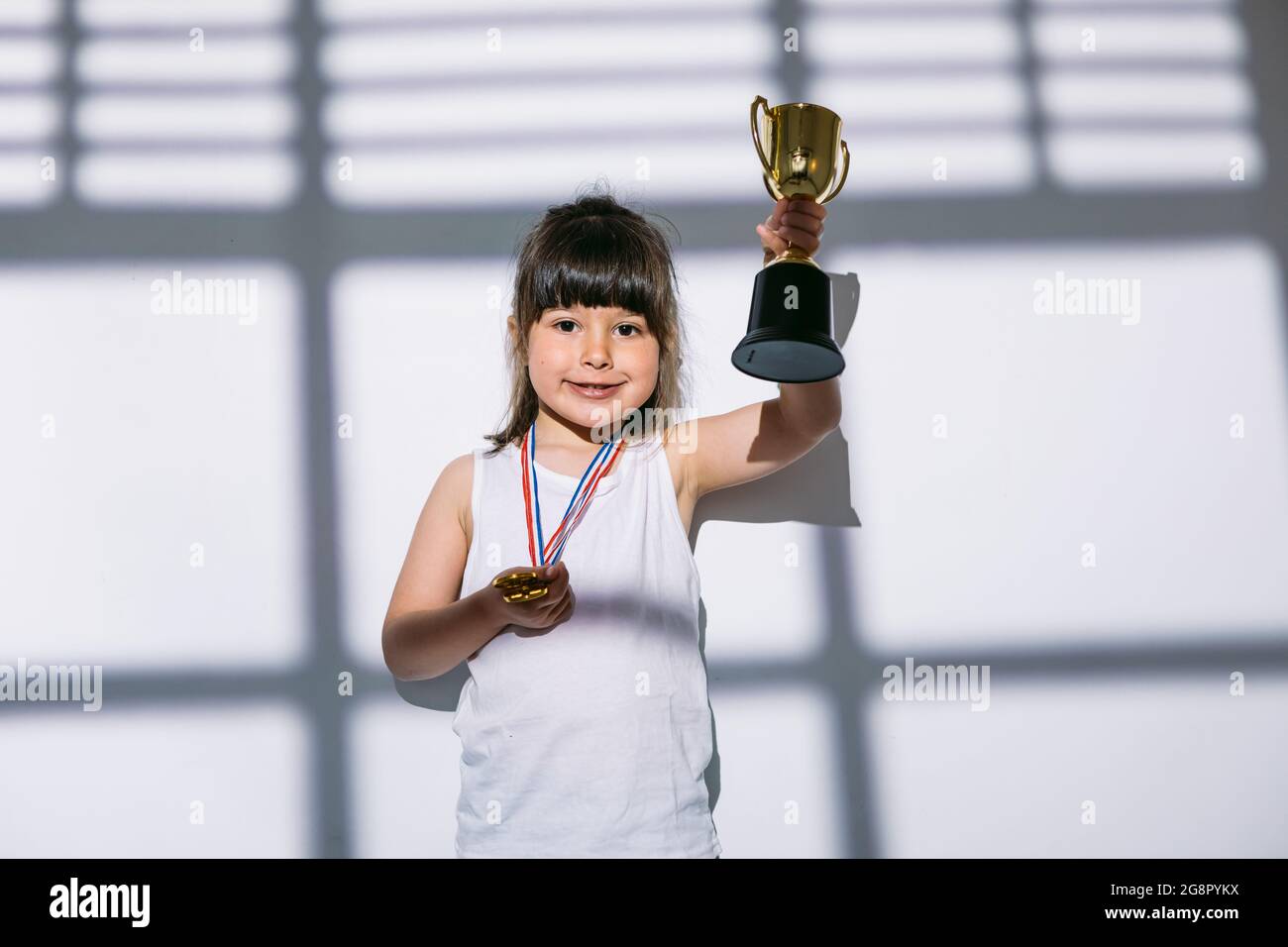 Dark-haired girl with sports championship medals, raising her trophy ...