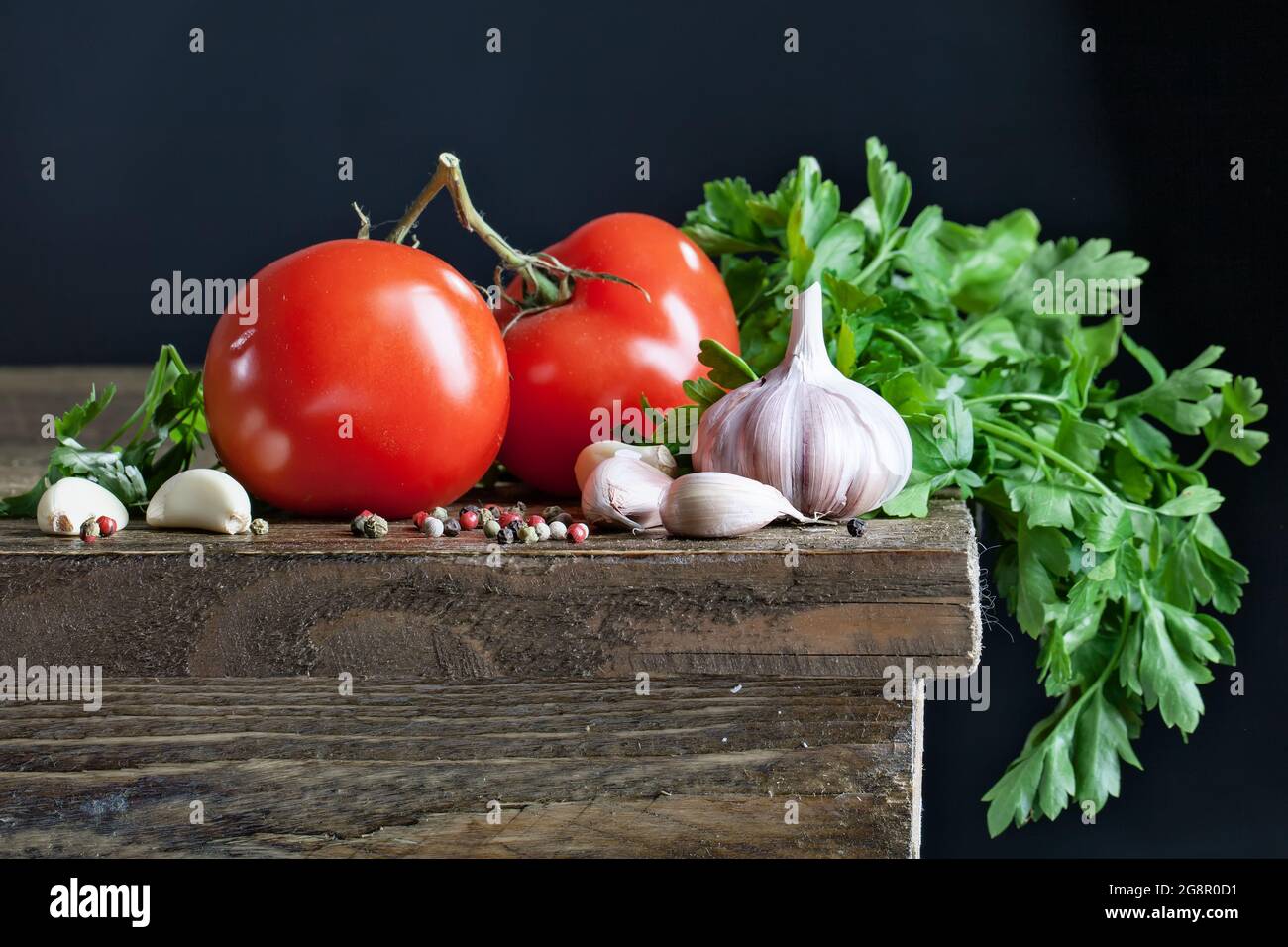 Tomatoes, garlic and herbs on the table on a dark background Stock ...