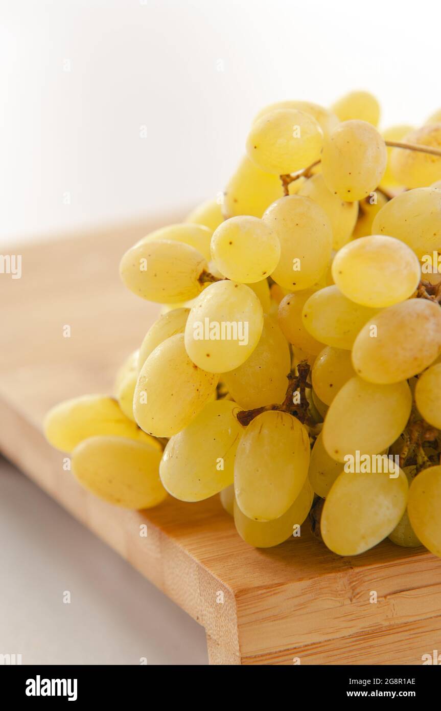 Vertical shot of fresh juicy grapes on a sharp wooden cutting board ...
