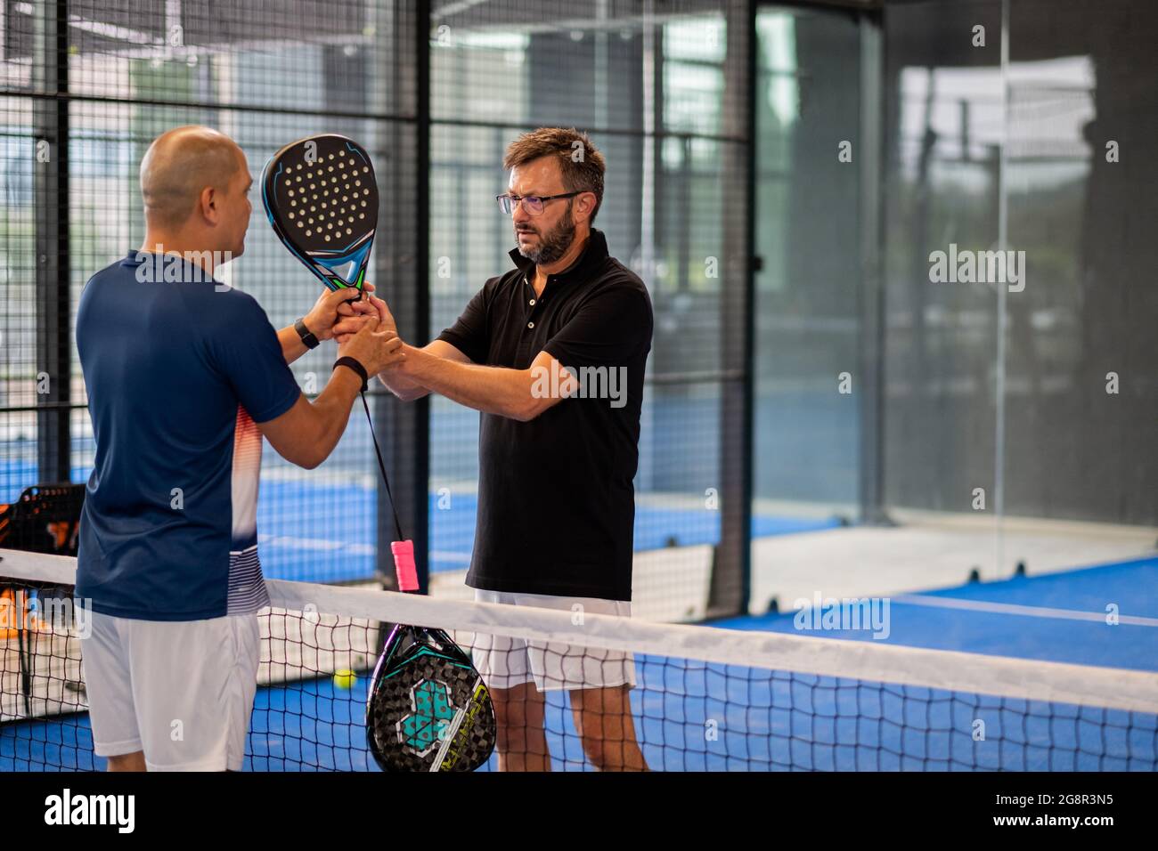 Monitor teaching padel class to man, his student - Trainer teaches boy ...