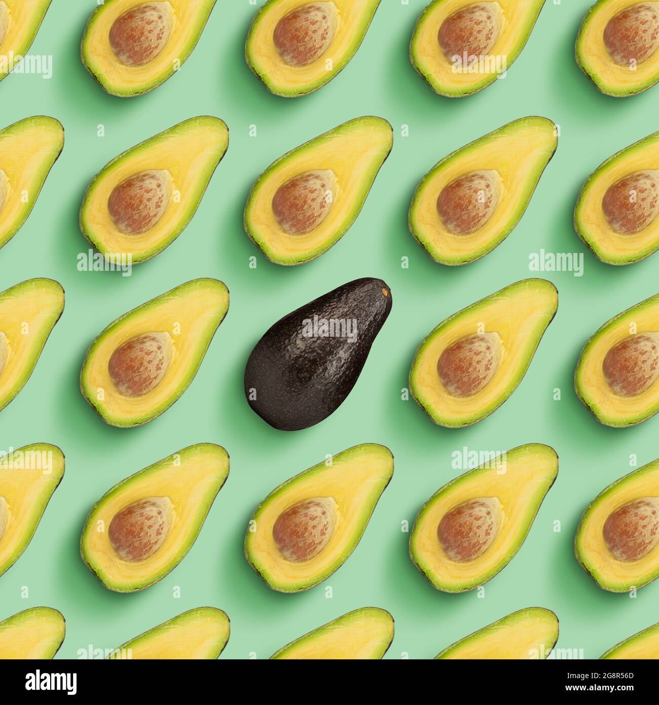 Halves and one whole ripe avocado arranged over light green background ...