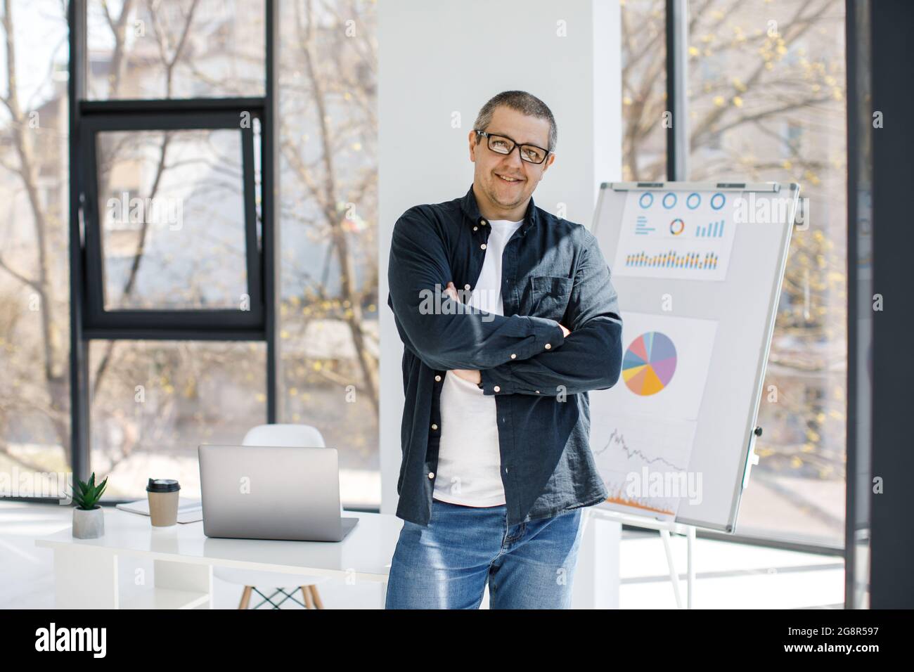 A man, strong physique, dressed in casual clothes works in the office ...