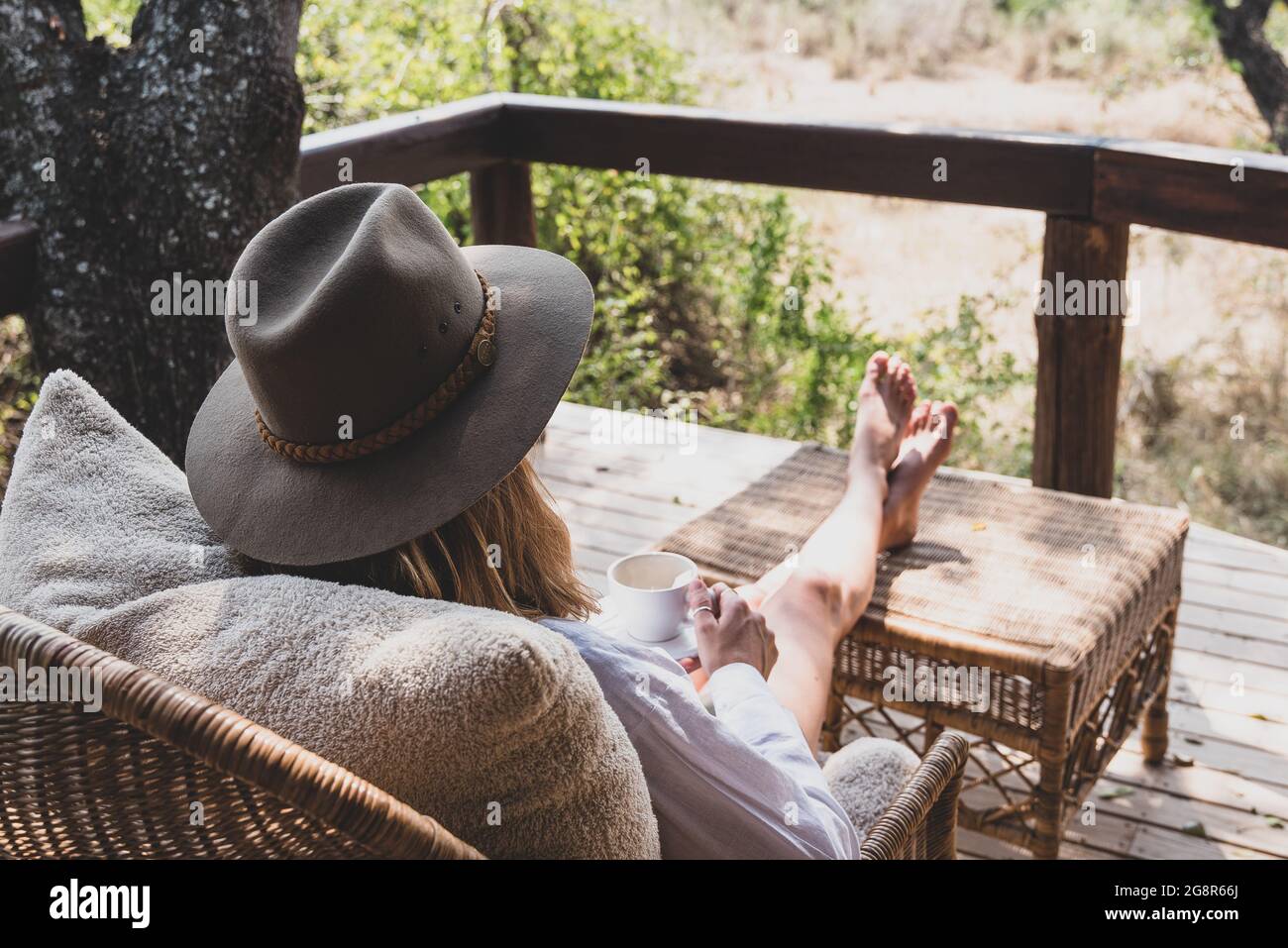A woman sits with her feet up drinking a cup of tea, wearing a safari ...