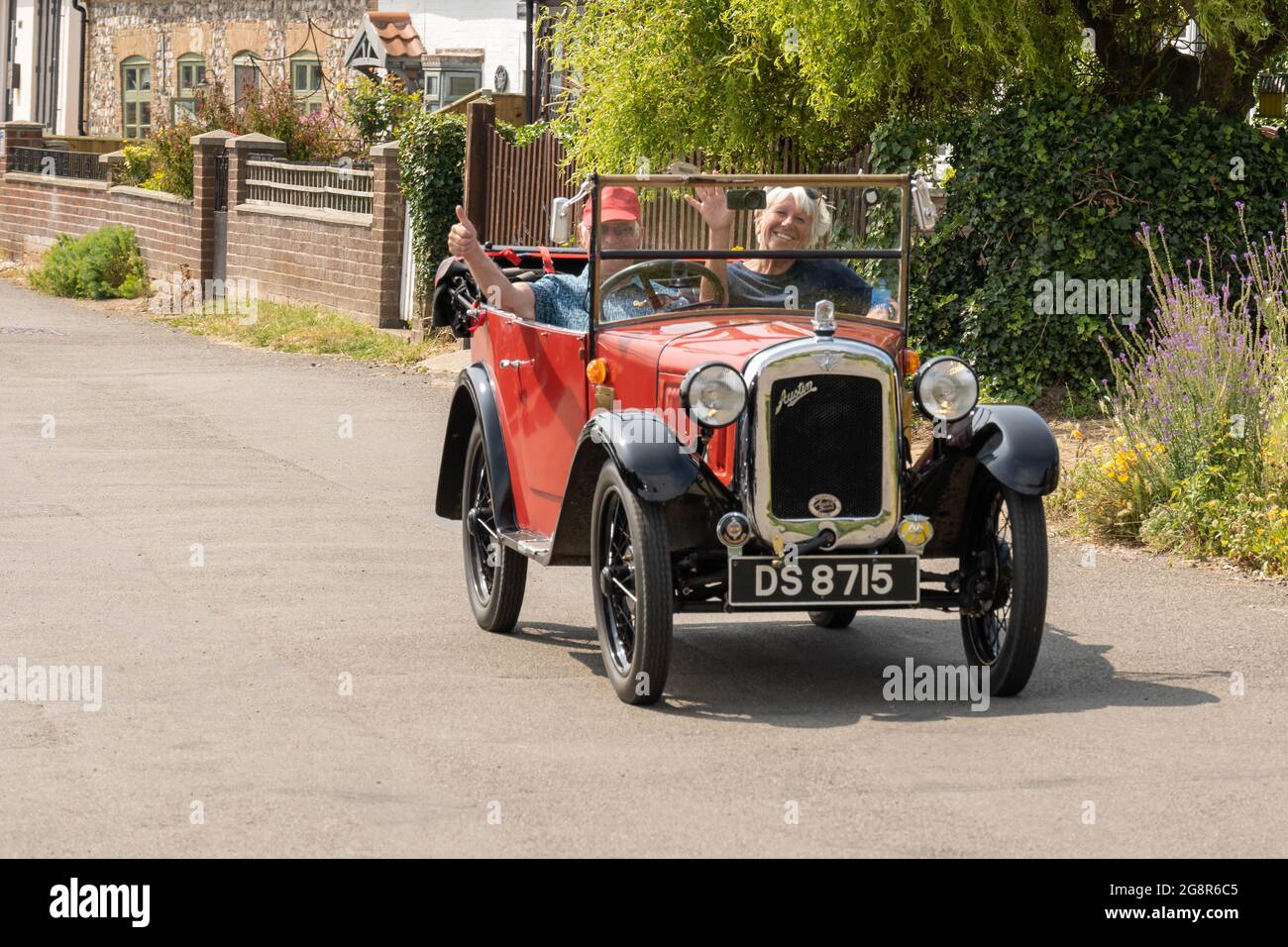 A red and black Austin seven convertible with man and woman in the ...