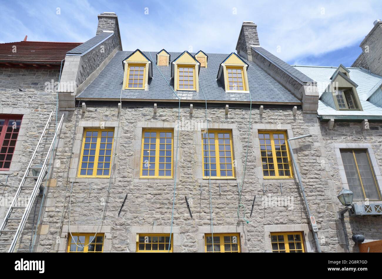 grey stone building with yellow windows under construction with ropes ...