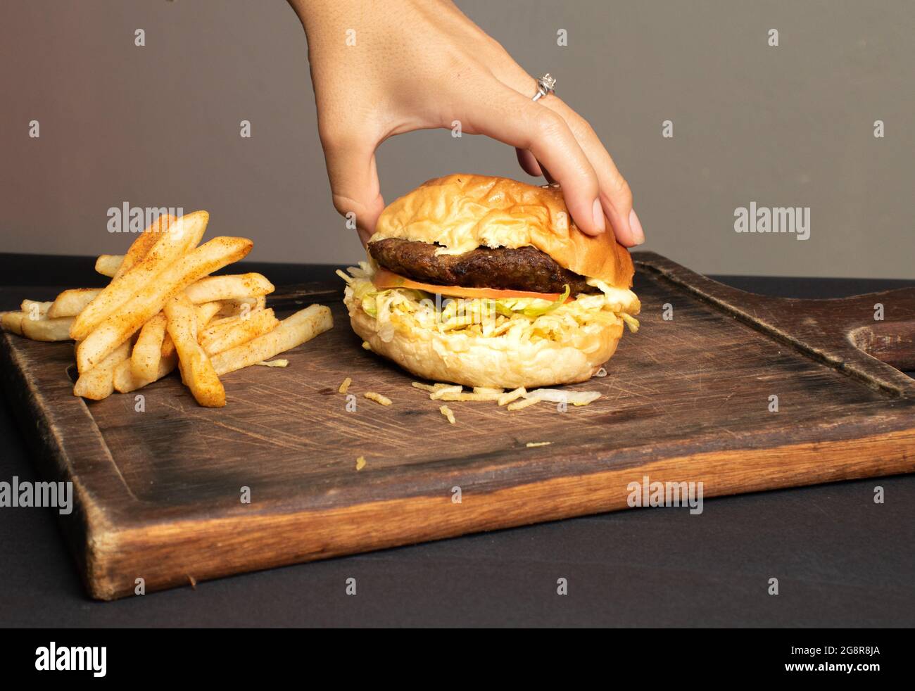 Hand opening a burger to see what is inside Stock Photo - Alamy