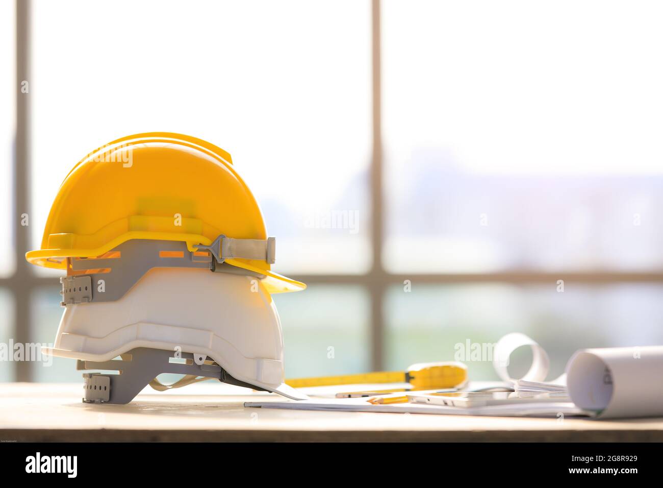 White and yellow safety helmet in construction site, light from big ...