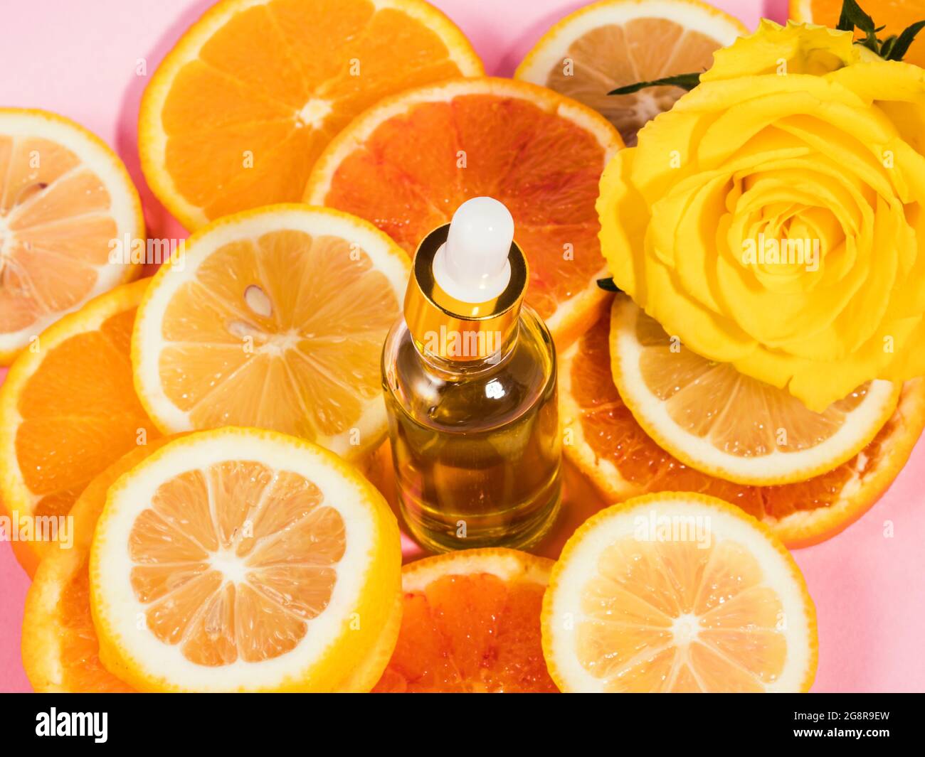 Vitamin C serum bottle with dropper on pink background with orange ...