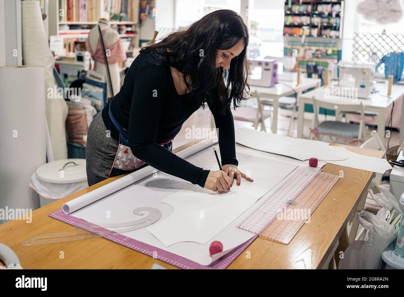 Seamstress working in bright and small fashion workshop. She is making ...