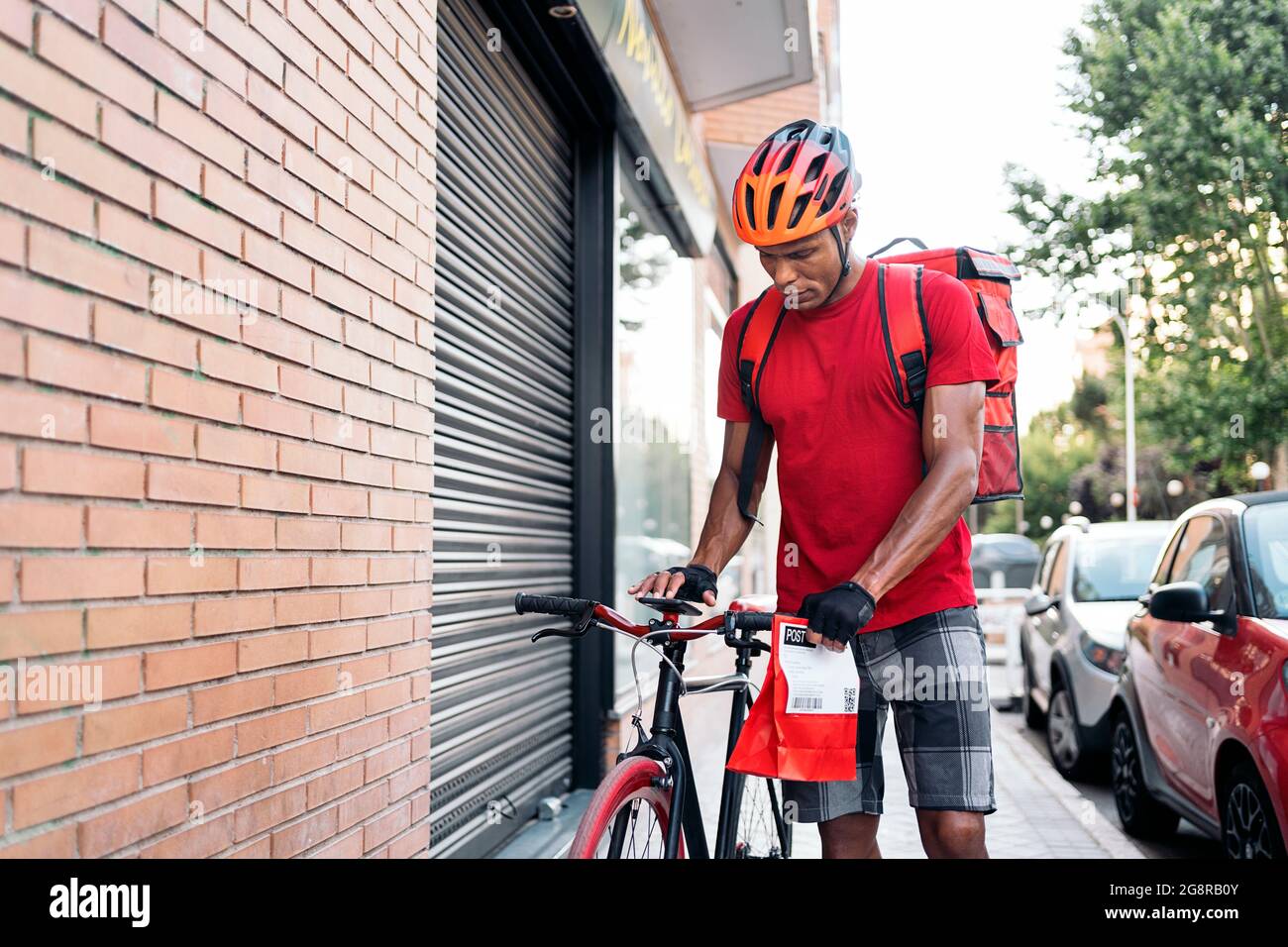 Messenger man using his phone in the street in his way to deliver a ...