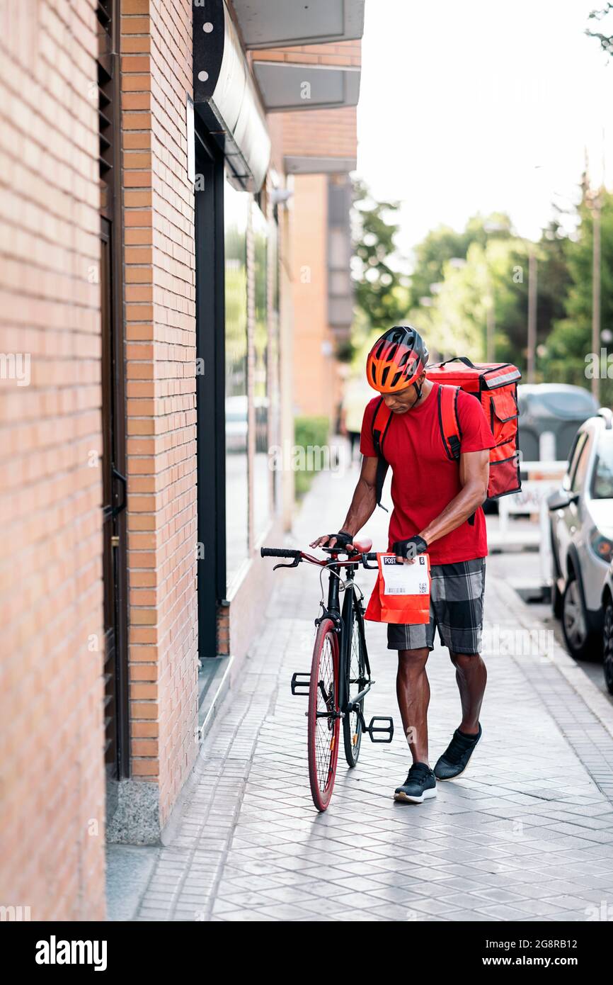 Messenger man using his smart-phone in the street in his way to deliver ...