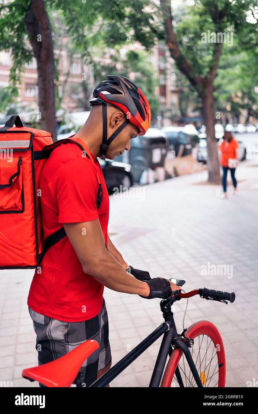 Messenger man using his smart-phone in the street in his way to deliver ...