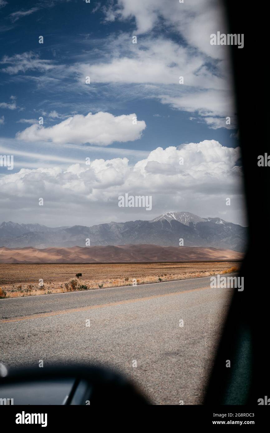 Vertical shot of a road and a beautiful mountain view through a window ...