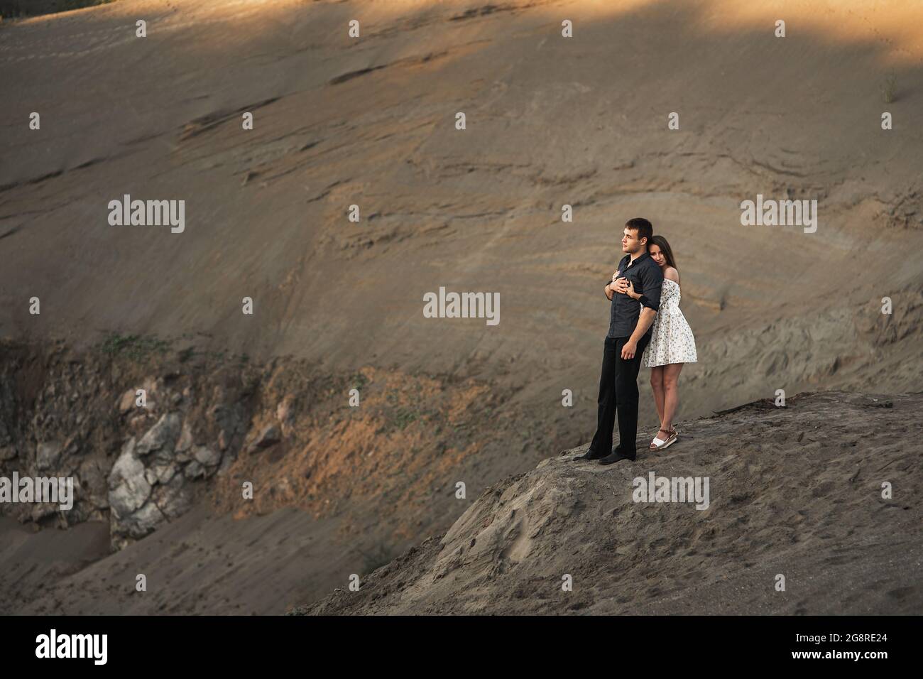 Young man and girl are higging on the bank of lake in nature. Couple in ...